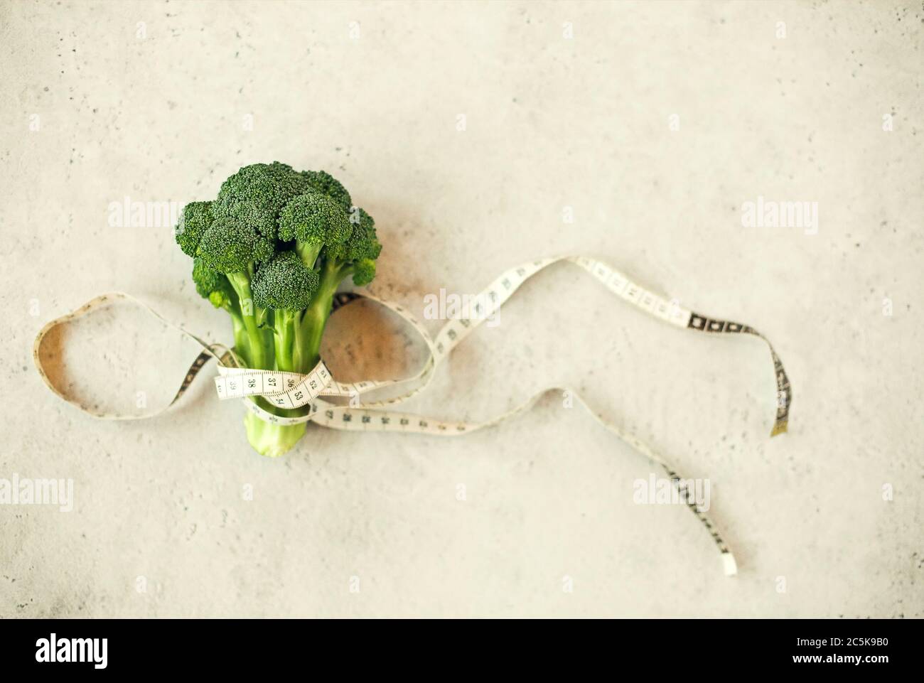 Top view of ripe broccoli with tied tape measure placed on beige ...