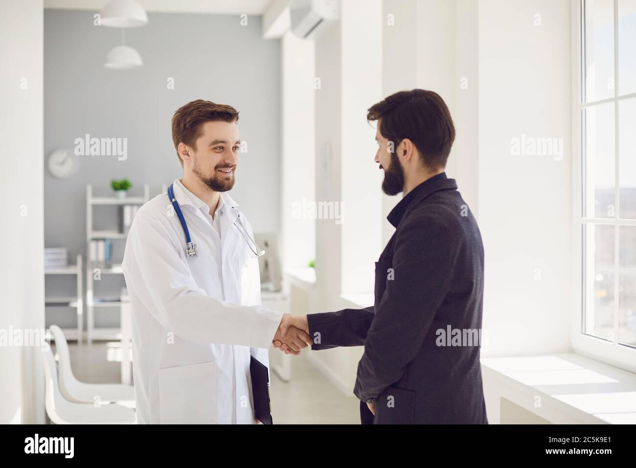 Handshake. Practicing doctor and patient shaking hands smiling at the ...