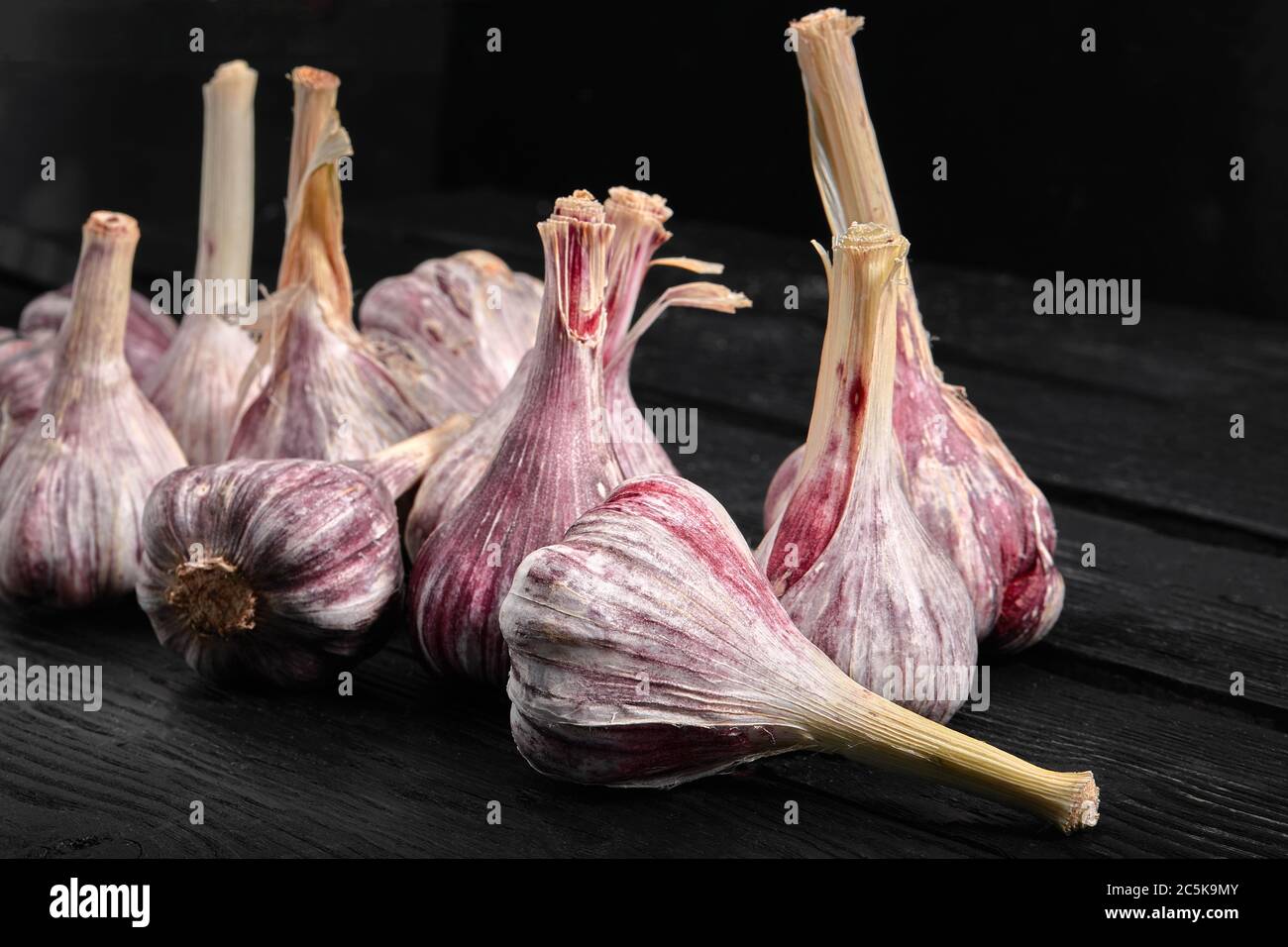 Food photo of red garlic on dark wooden background, side view. Organic ...
