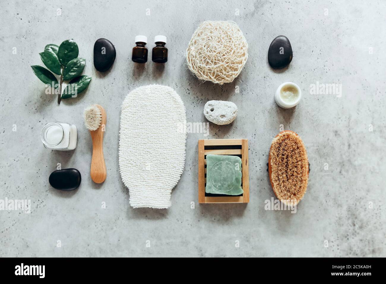 Flat lay of assorted spa tools and cosmetics placed on gray stone ...