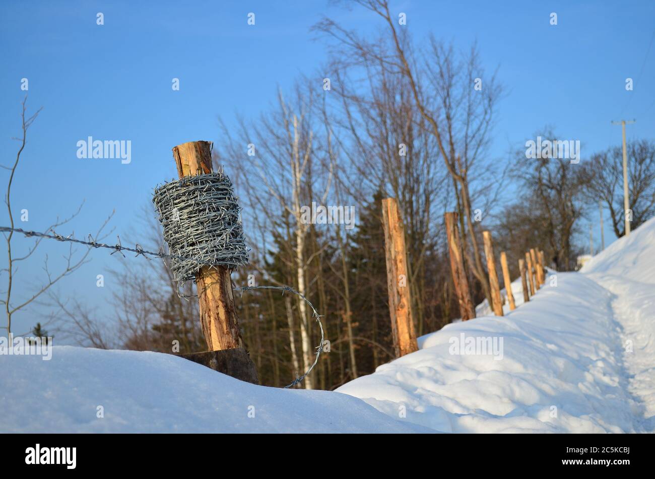 Reel of barbed wire on a wooden pale, part of half done barbed wire ...
