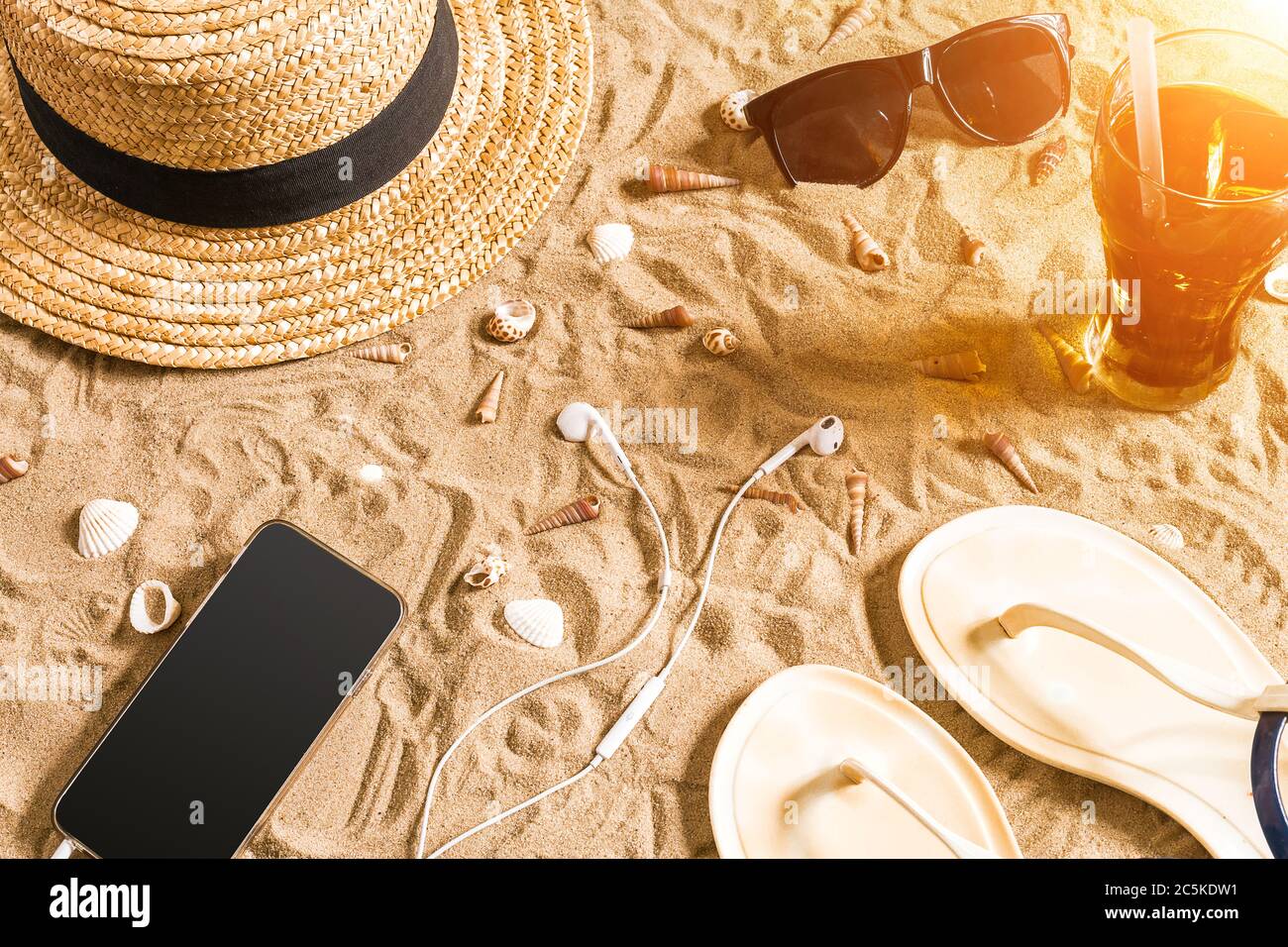 Summer beachwear, flip flops, hat, sunglasses and seashells on sand ...