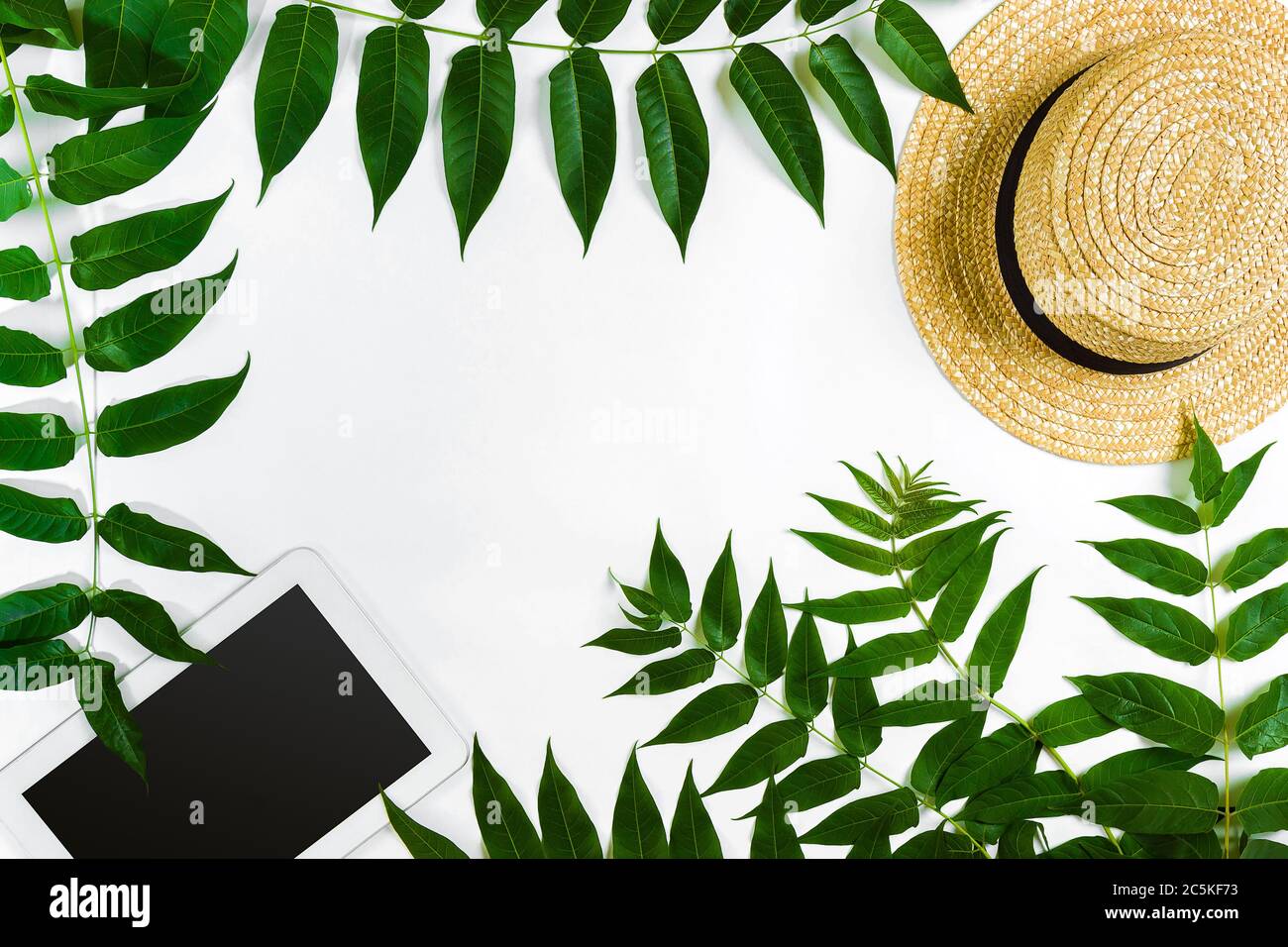 Green leaf branches, tablet and straw haton white background. flat lay ...