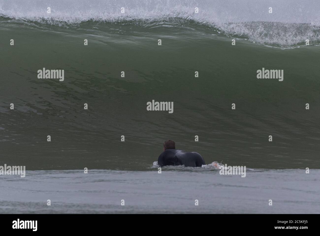 Unlucky surfer in black wetsuit gets caught inside and has to duck dive ...
