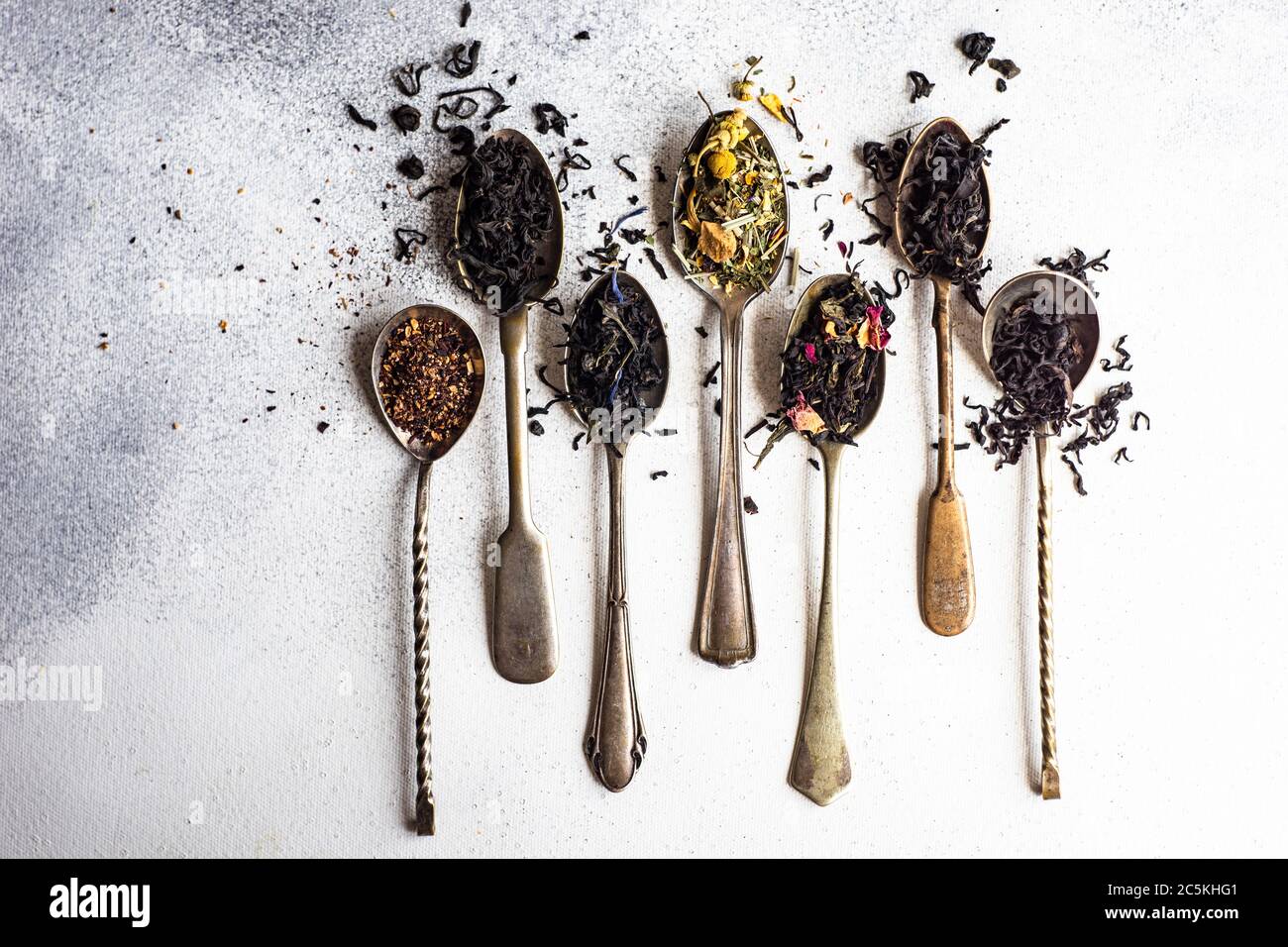 Varieties of tea in vintage spoons on concrete background with copy ...