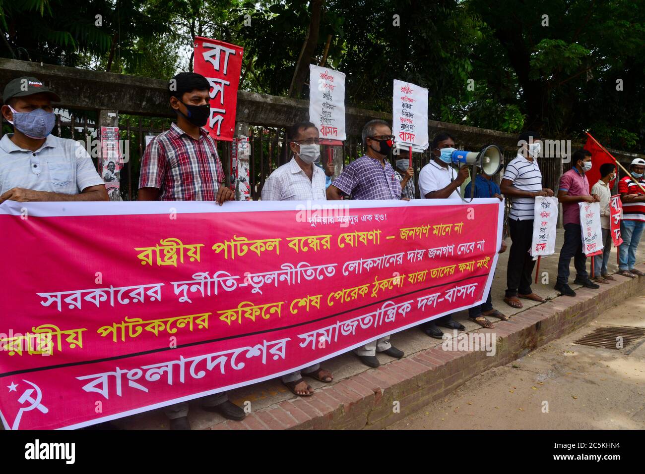 Bangladesh's left wing party supporters stand behind a banner and hold ...