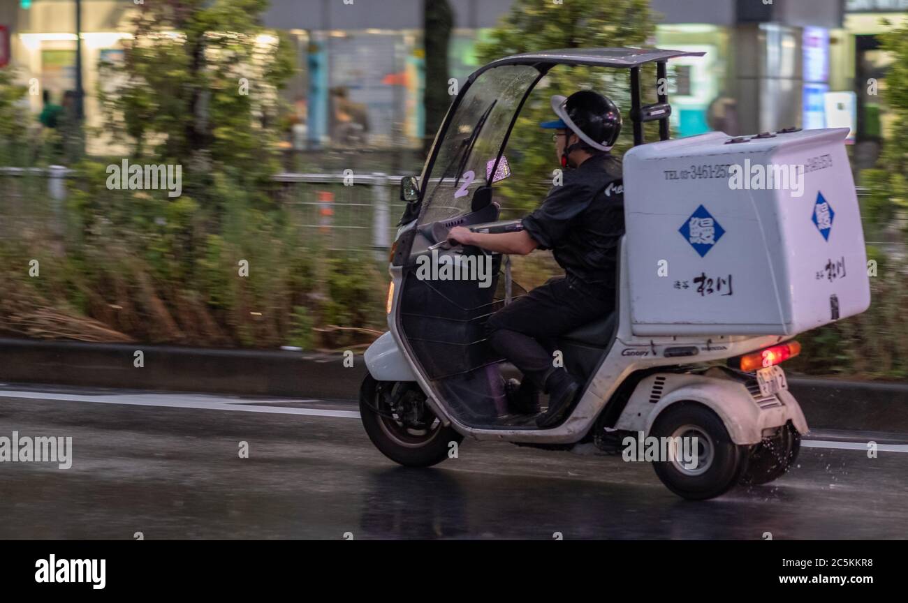 Motorcycle delivery man in the street of Shibuya, Tokyo, Japan during a ...