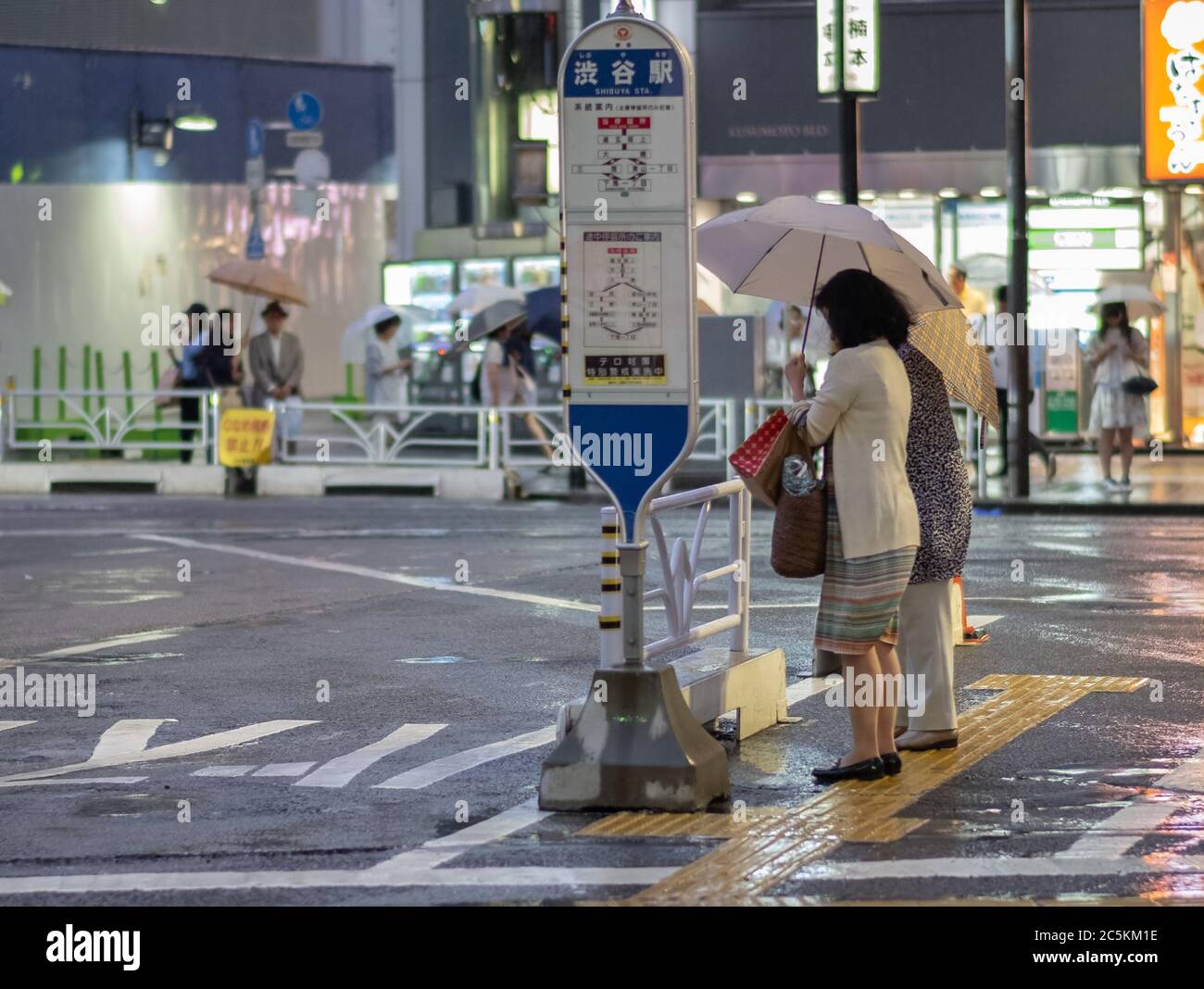 Passengers waiting for a bus in Shibuya Station, in a rainy night ...