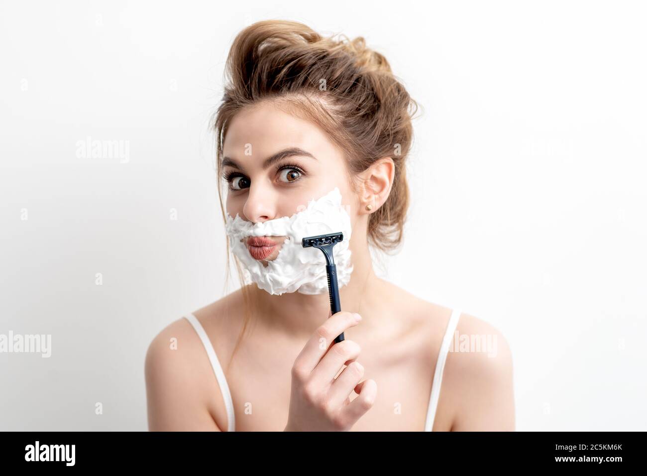 Beautiful young caucasian woman shaving her face by razor on white ...