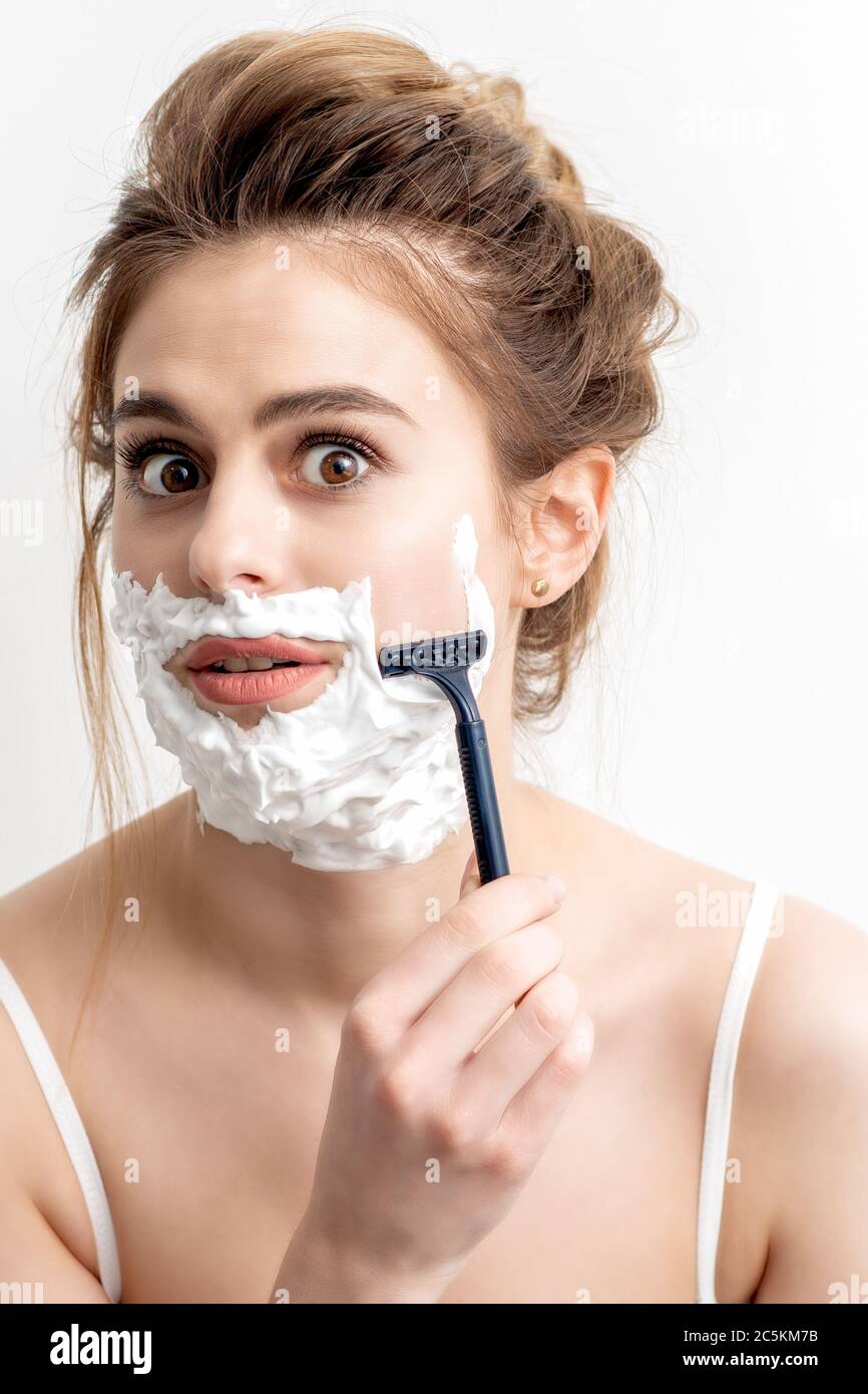 Beautiful young caucasian woman shaving her face by razor on white ...