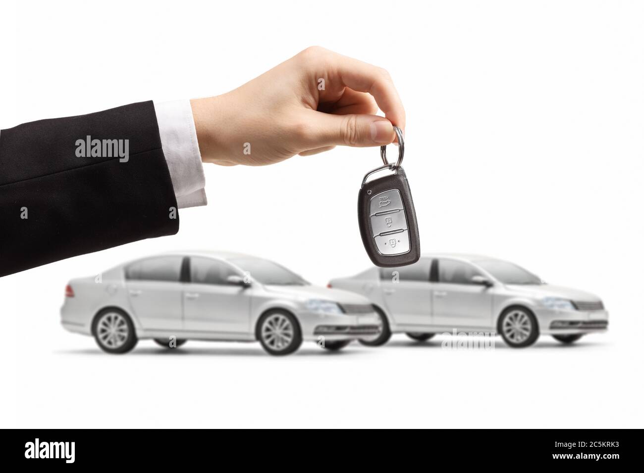 Two identical silver cars and a male hand holding a key isolated on ...