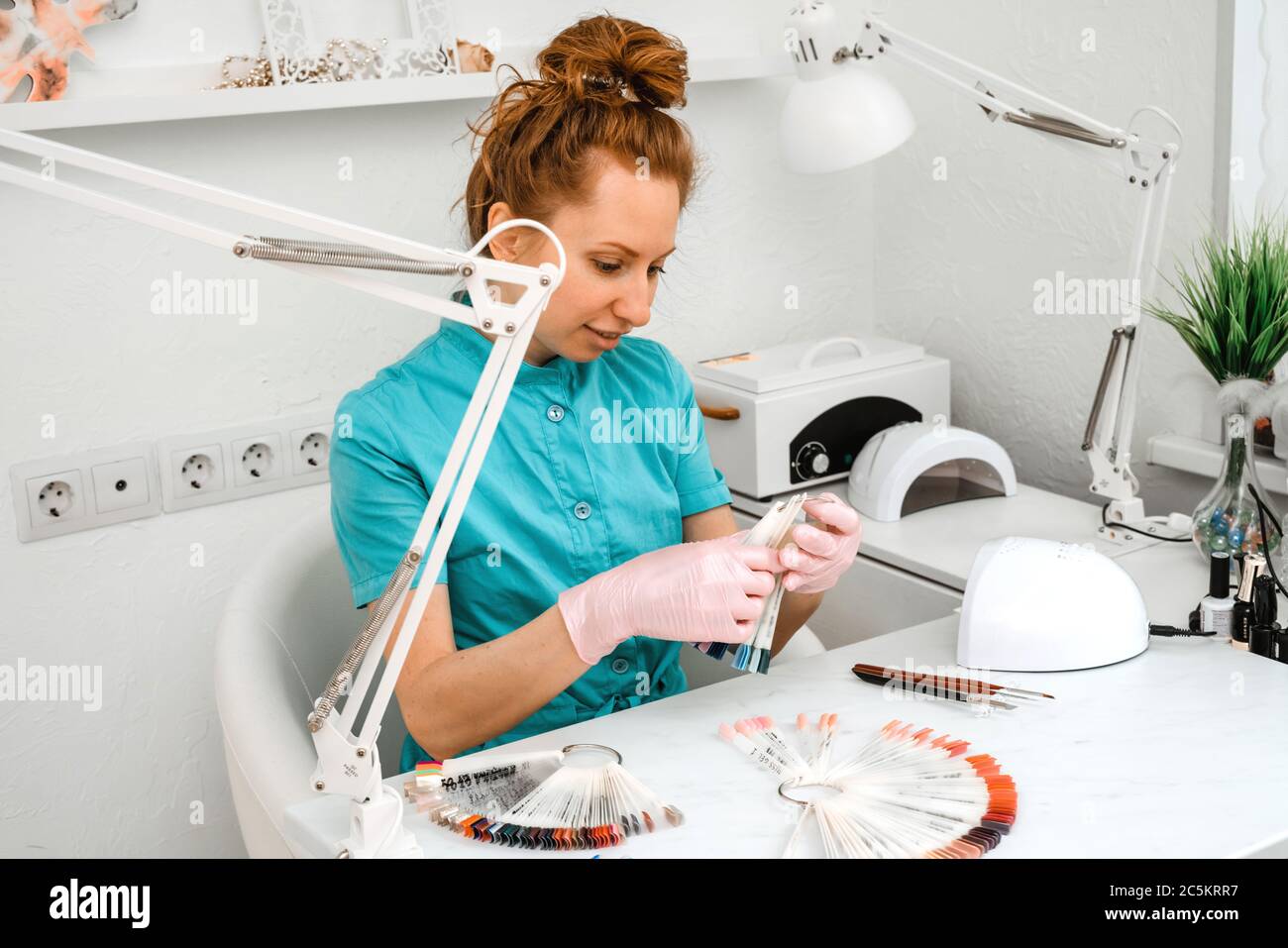 Manicurist at work in the office. Drawing gel polish on tips, creating ...