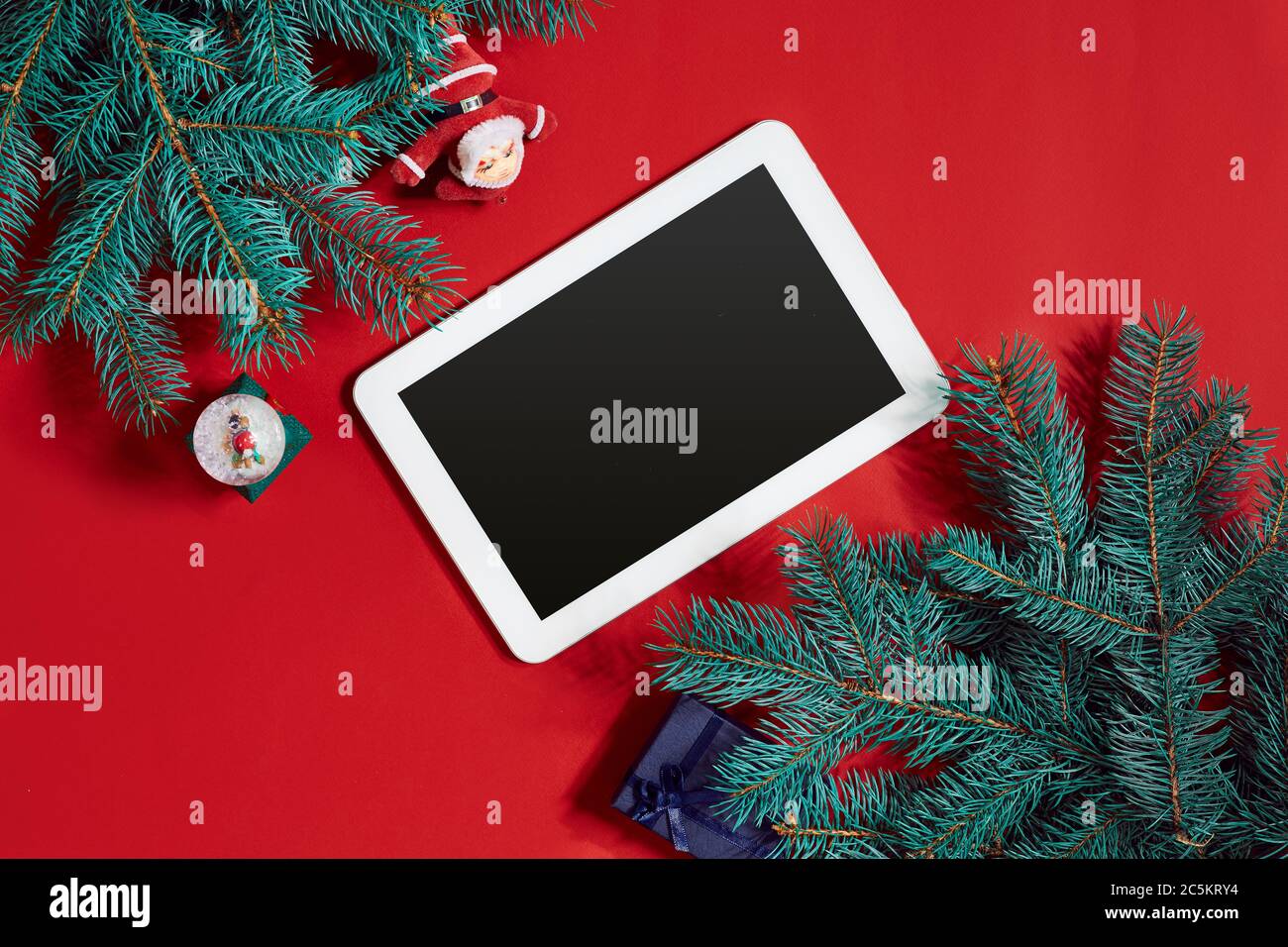 Christmas decorations and white tablet with black screen on hot red ...