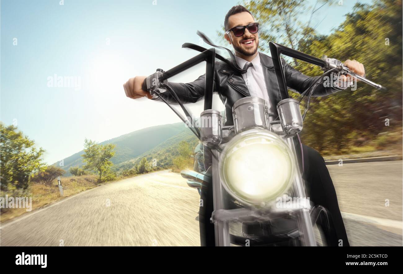 Man riding a chopper motorbike on an open road in a picturesque area ...