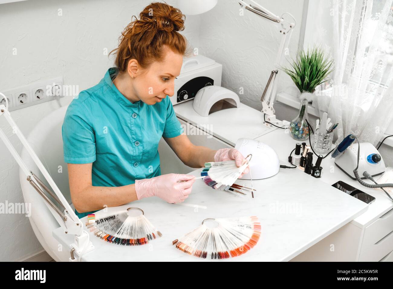 Manicurist at work in the office. Drawing gel polish on tips, creating ...