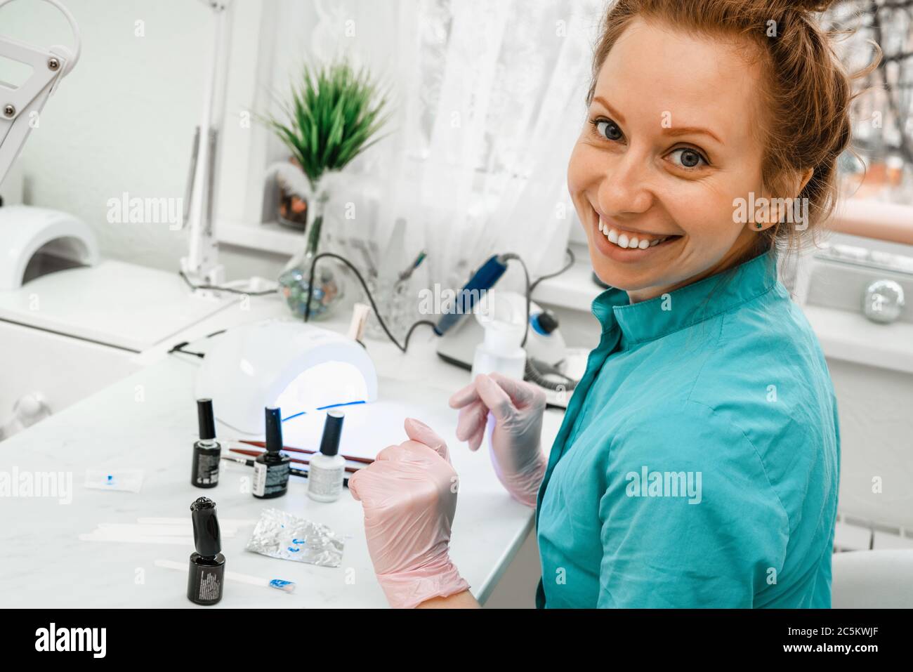Manicurist at work in the office. Drawing gel polish on tips, creating ...