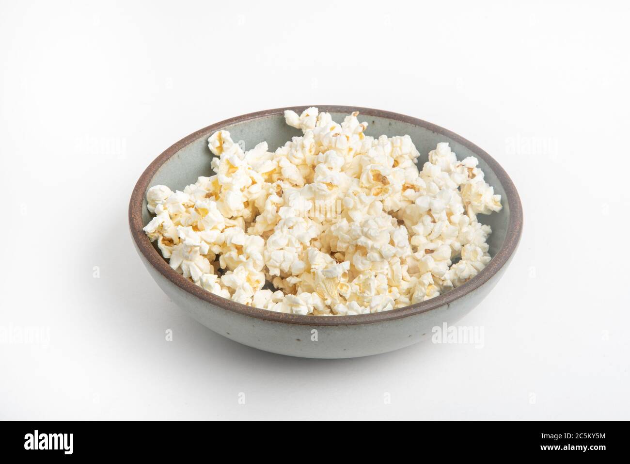 Popcorn in a ceramic bowl set on a plain white background Stock Photo ...