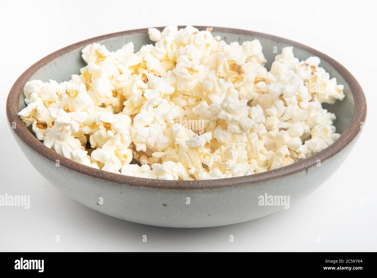 Popcorn in a ceramic bowl set on a plain white background Stock Photo ...