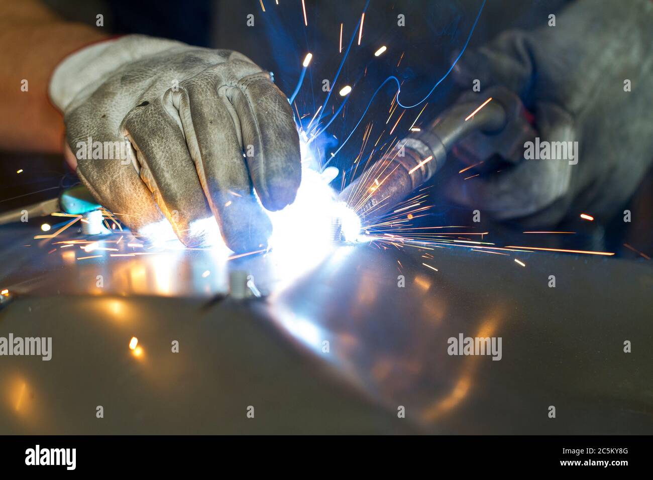 Close up on a welding machine in action, handheld by a worker wearing ...