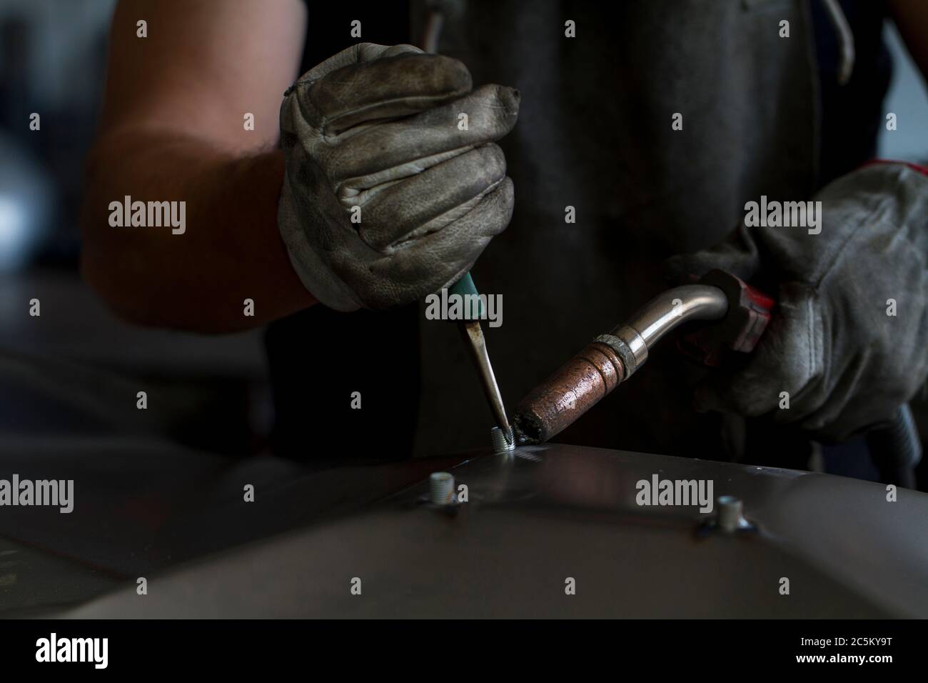 Close up on a welding machine in action, handheld by a worker wearing ...