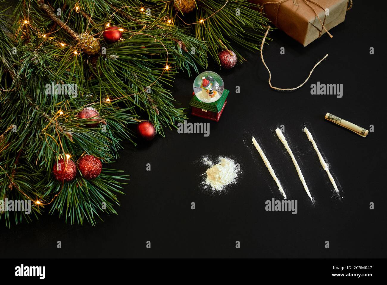 Cocaine divided into paths with Xmas toys and spruce branch on black ...