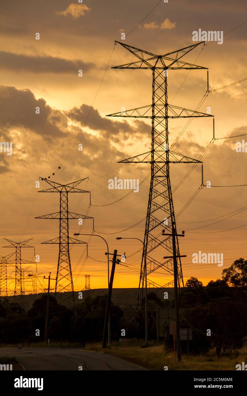 Electricity pylons in a row at sunset Stock Photo - Alamy