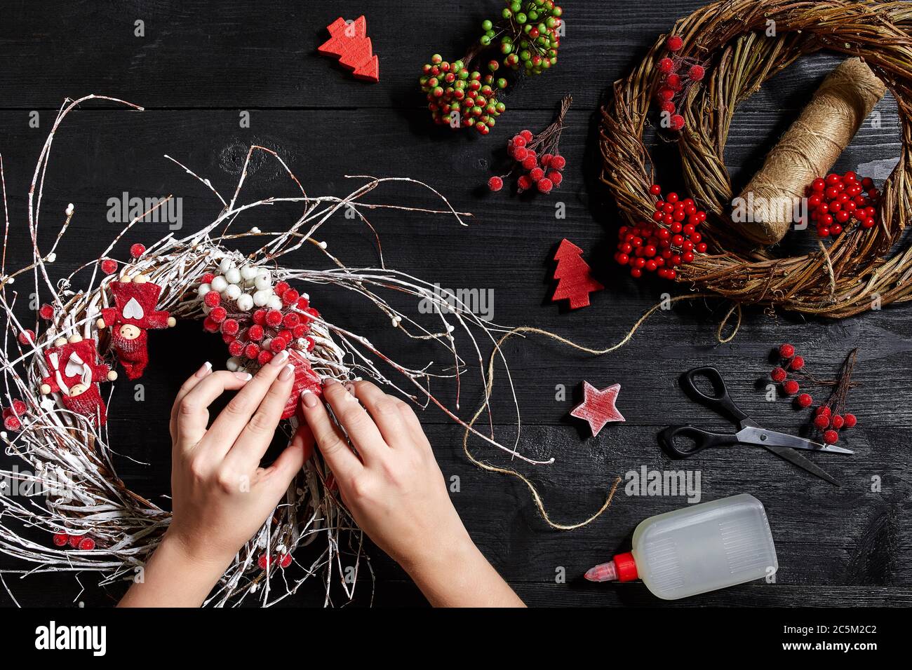 Top view of female hands make a Christmas wreath. Packed gifts and scrolls, spruce branches and ...