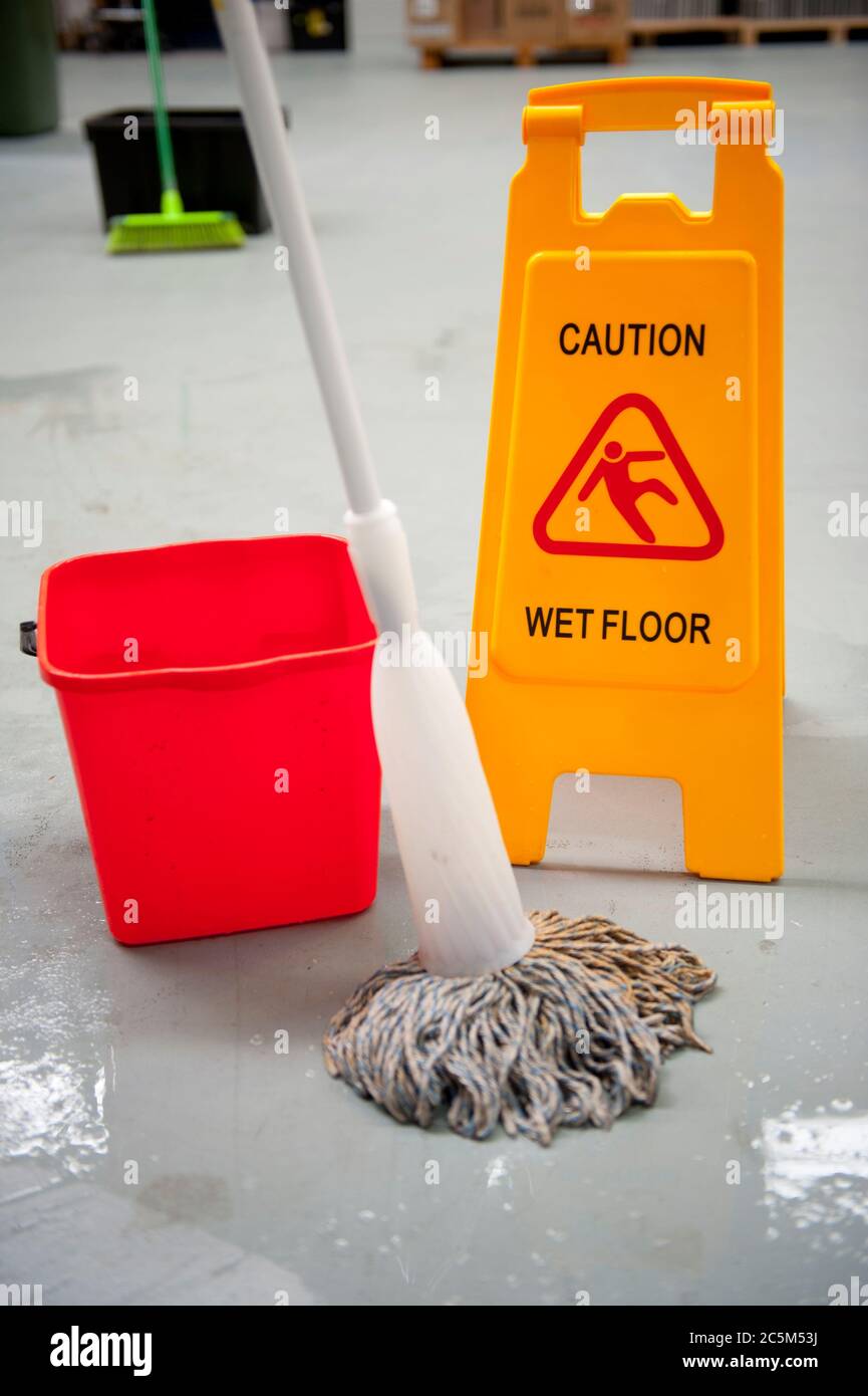 Wet floor in warehouse with Caution Cleaning Sign and mop Stock Photo ...
