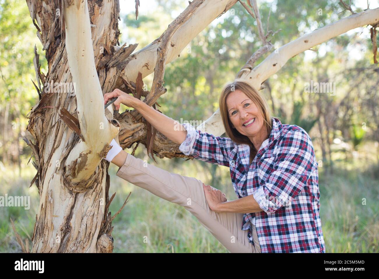 Portrait active fit and sporty mature woman stretching in the forest ...
