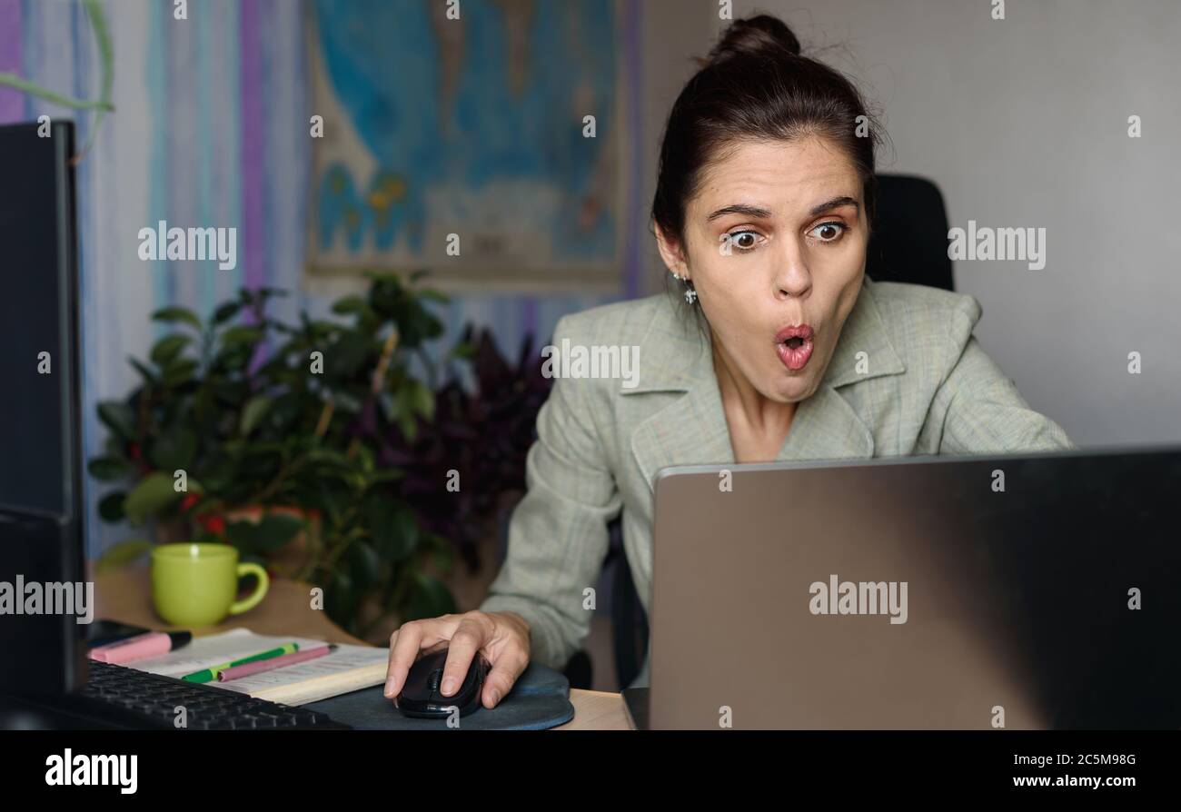 Shocked business woman using laptop looking at computer screen at home ...