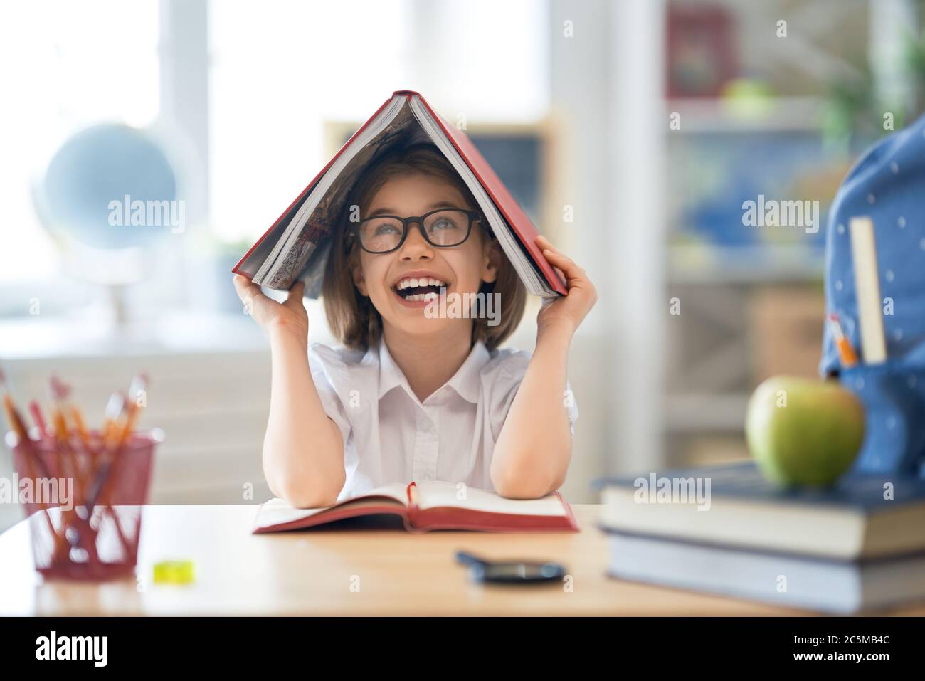Back to school! Happy cute industrious child is sitting at a desk ...