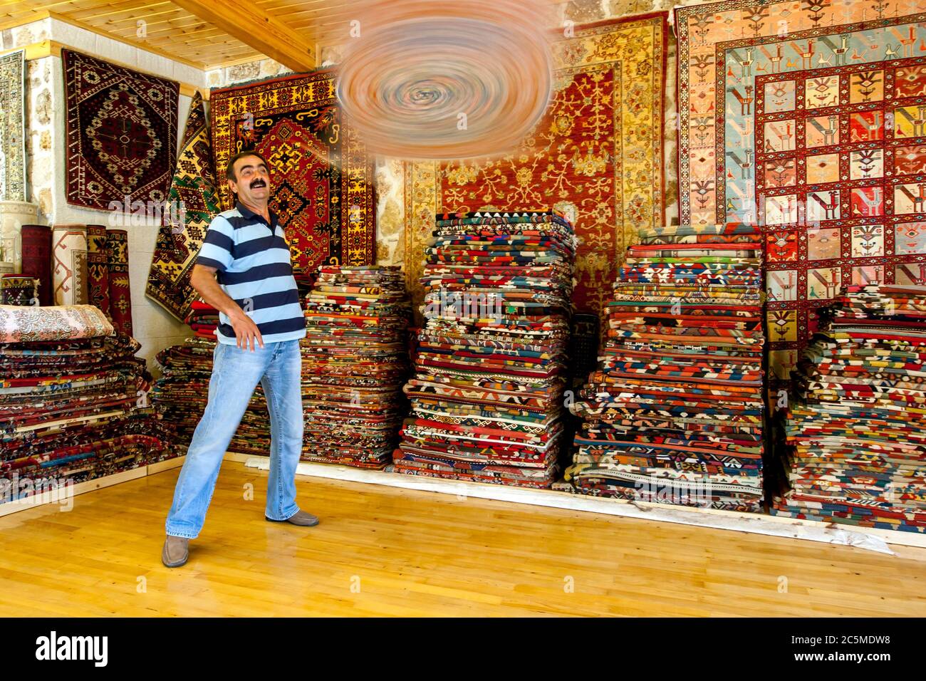 A Turkish carpet seller shows his skills at carpet spinning at his shop ...