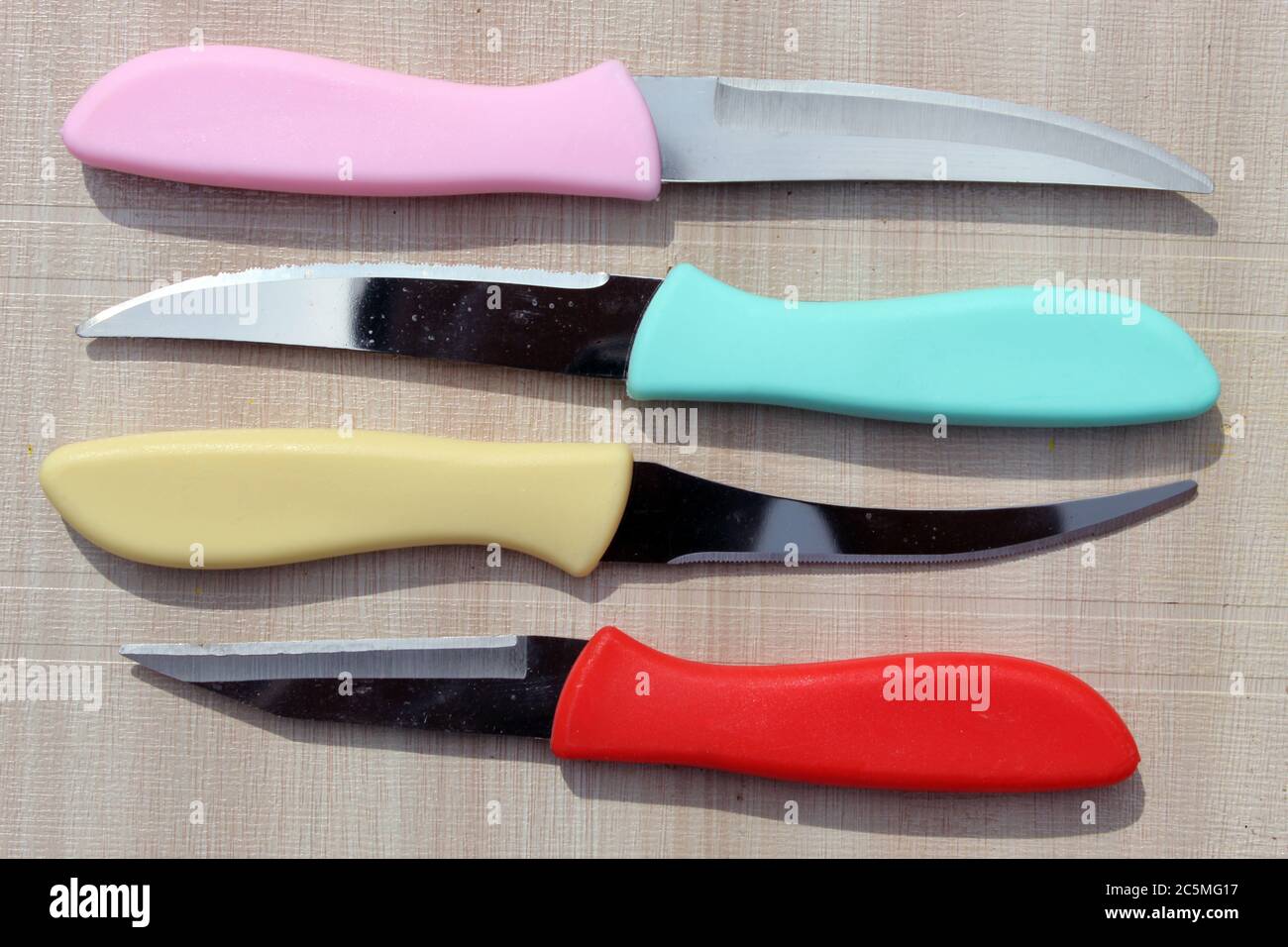 Colorful knives close display on a white texture surface. Cutter and ...