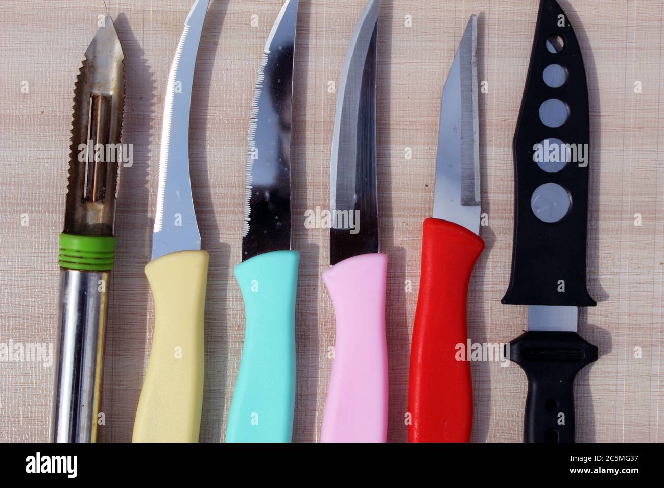 Colorful knives close display on a white texture surface. Cutter and ...