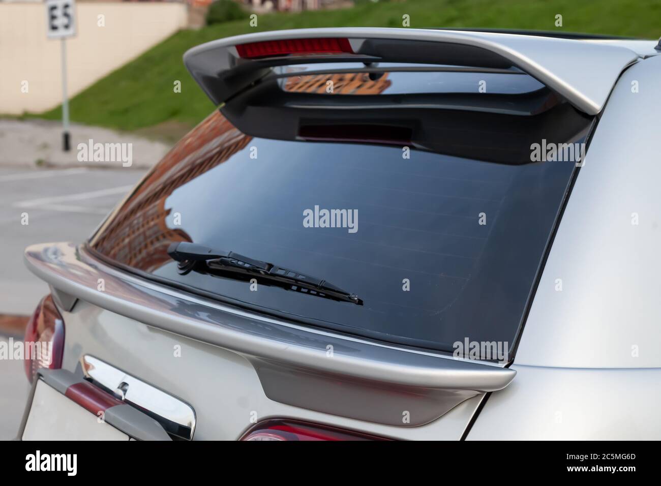 Rear view of a gray glass hatchback with a spoiler in a car parking ...