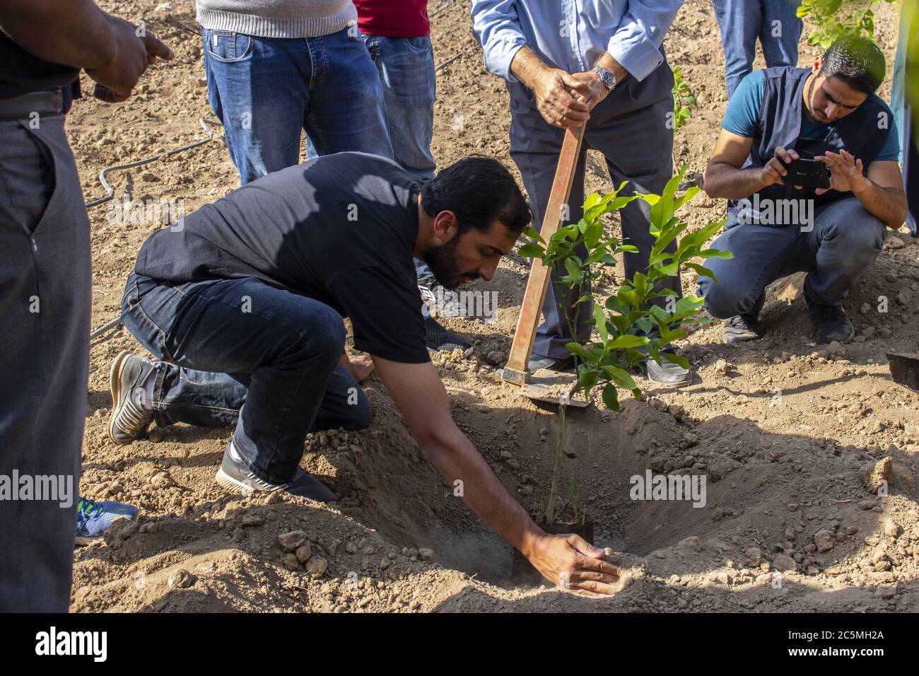 a group of different ages is planting saplings during the earth day in ...