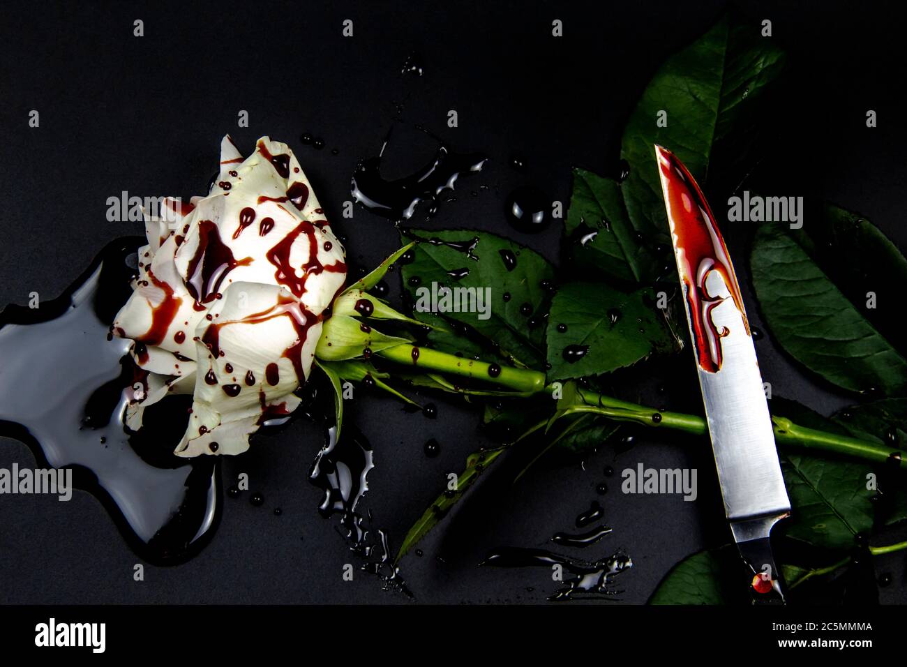 Beautiful and bloody white rose with knife on the dark background ...