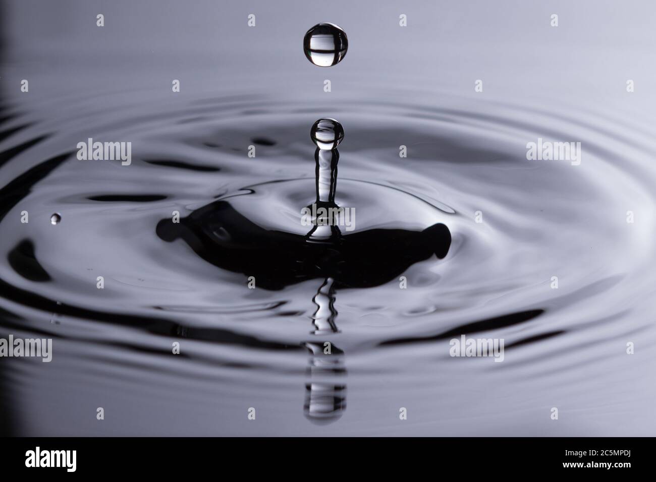 Perfect water drop splashing into smooth water causing ripples Stock ...