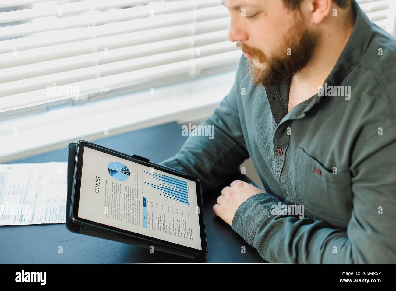 Economist working with graphs and diagrams on tablet at office Stock ...