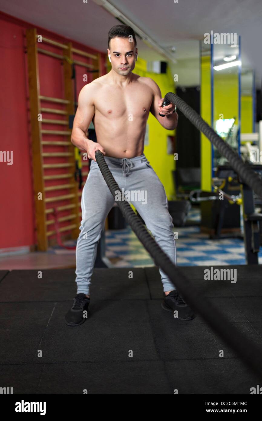 Muscular young man performing exercise with ropes, Inside a gym Stock ...
