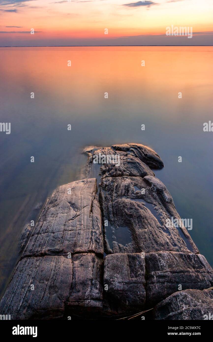 Cliffs at the water edge with flat water at sunset Stock Photo - Alamy