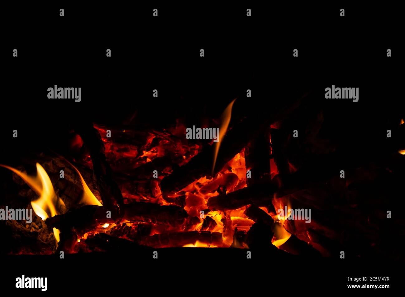 Red coals with fire on a black background. Burning coals and wood in ...