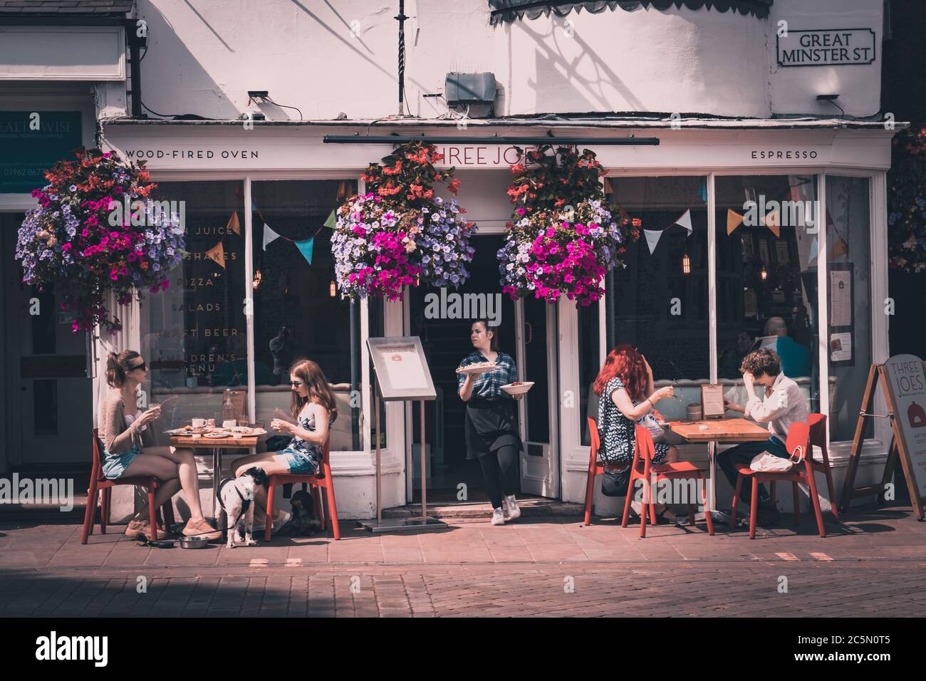 the front of a cafe with people sitting at tables in the sun enjoying ...