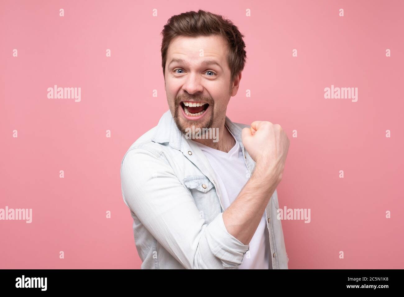 Young caucasian man expressing his excitement and delight by clenching ...