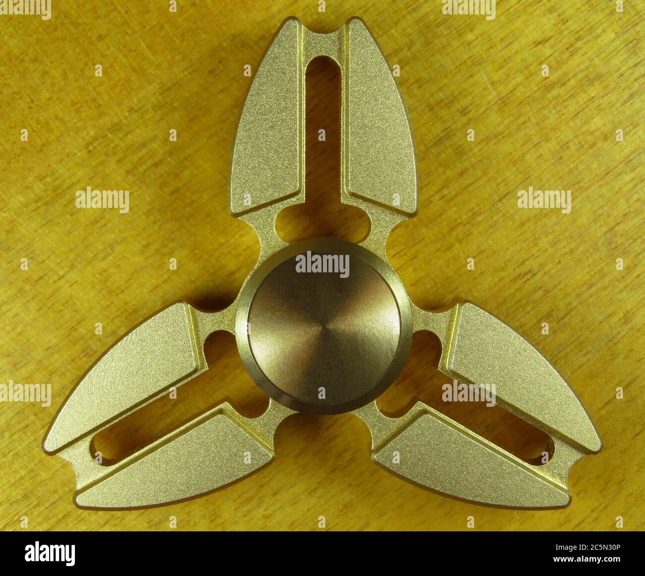 Golden fidget spinner toy on the wooden surface Stock Photo - Alamy