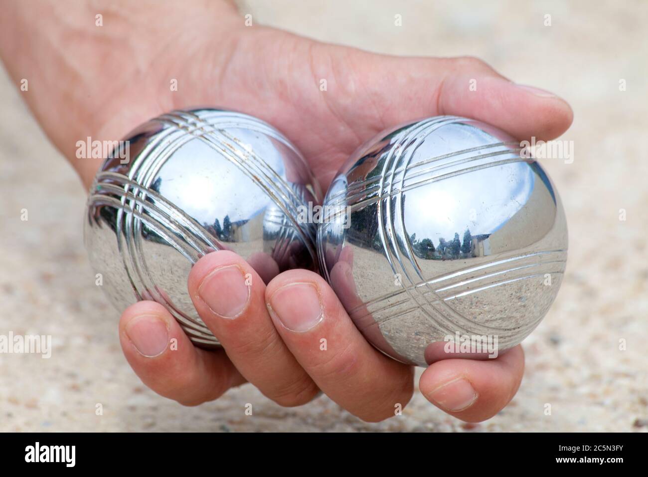 Hand is holding two Bocca balls to play Jeu de Boule, a typical French ...