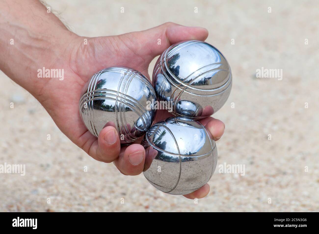 Hand is holding three Bocca balls to play Jeu de Boule, a typical ...