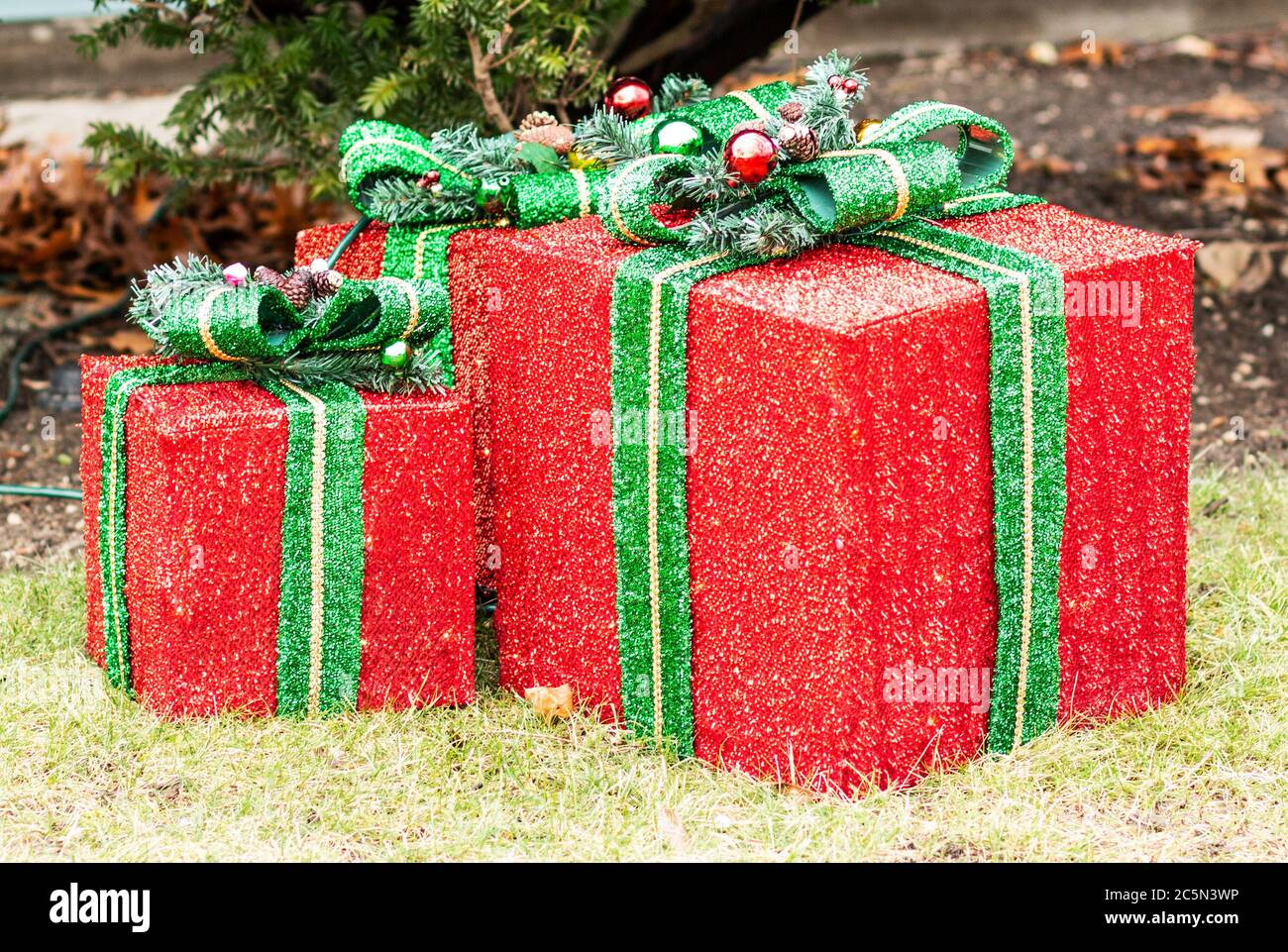 Three large red Christmas present ant ornaments with green bows outside ...