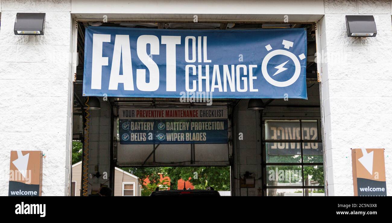 Large blue Fast Oil Change sign hangs over mechanics bay door with ...