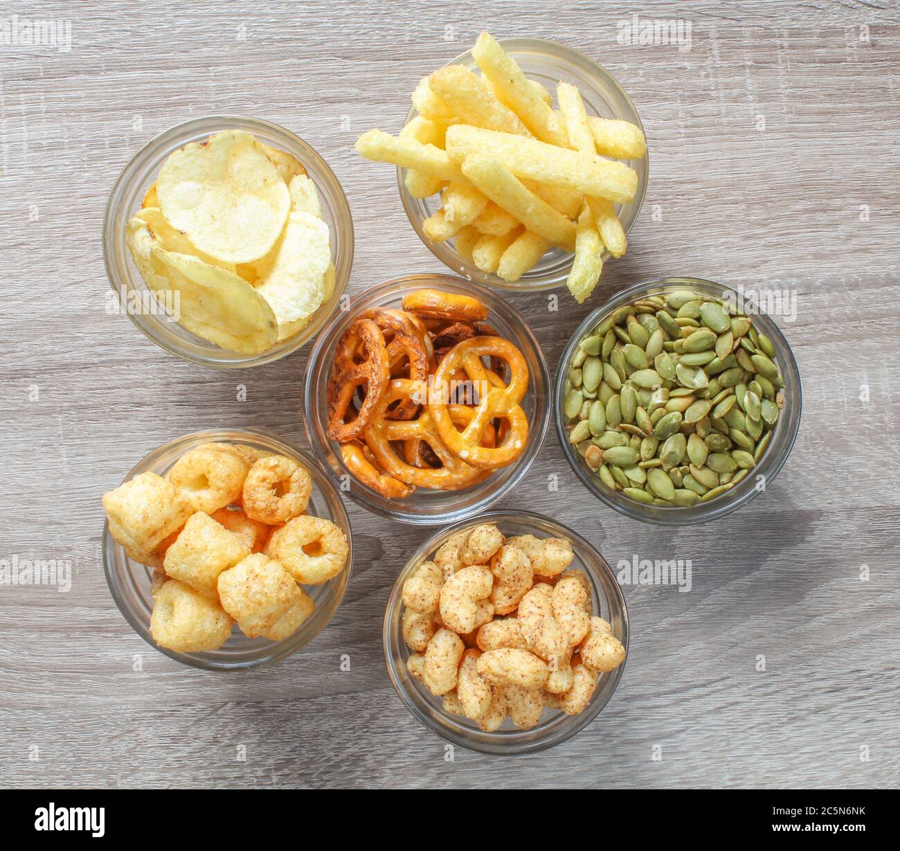 Top view of different types of snacks on wooden table. Crisps and ...